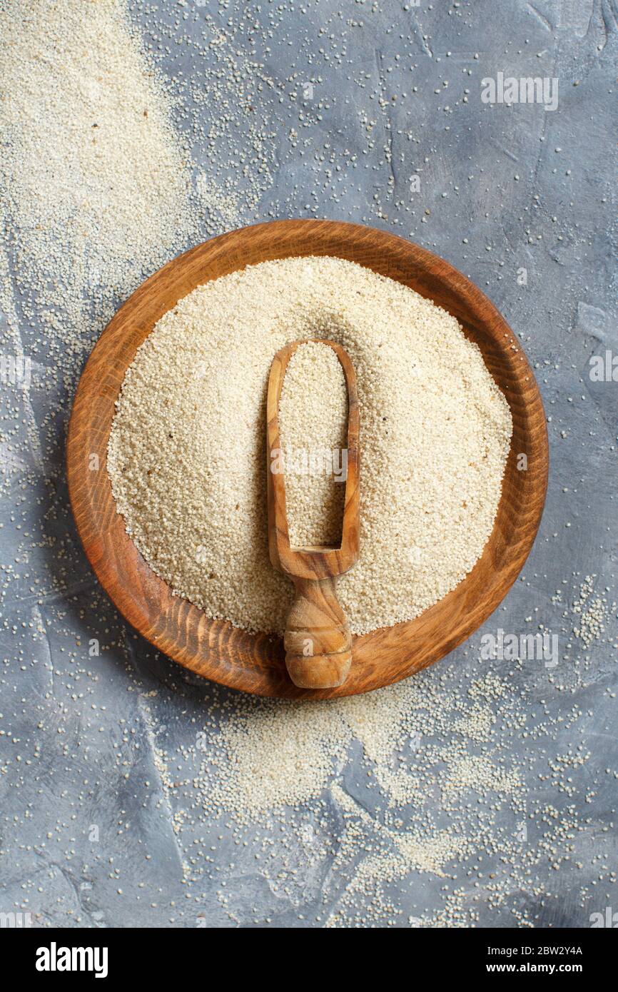 Raw uncooked fonio seeds with a spoon on a plate on grey background top ...