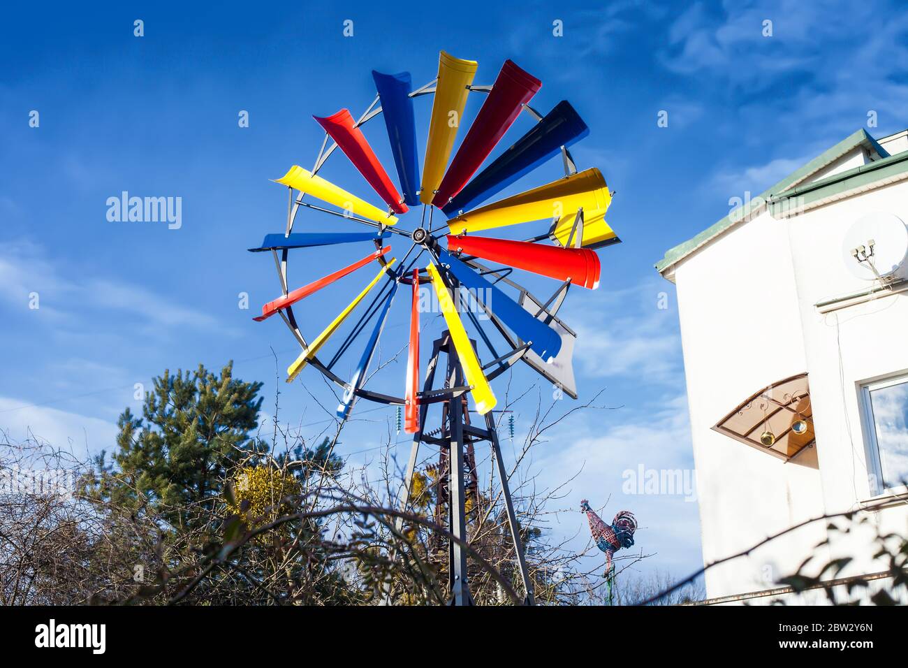 Multicolor small windmill by blue sky. Small wind turbine near house ...