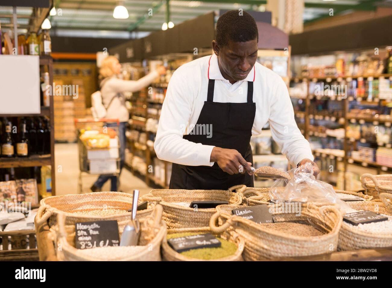 Portrait of African American salesman selling bulk foods in grocery ...