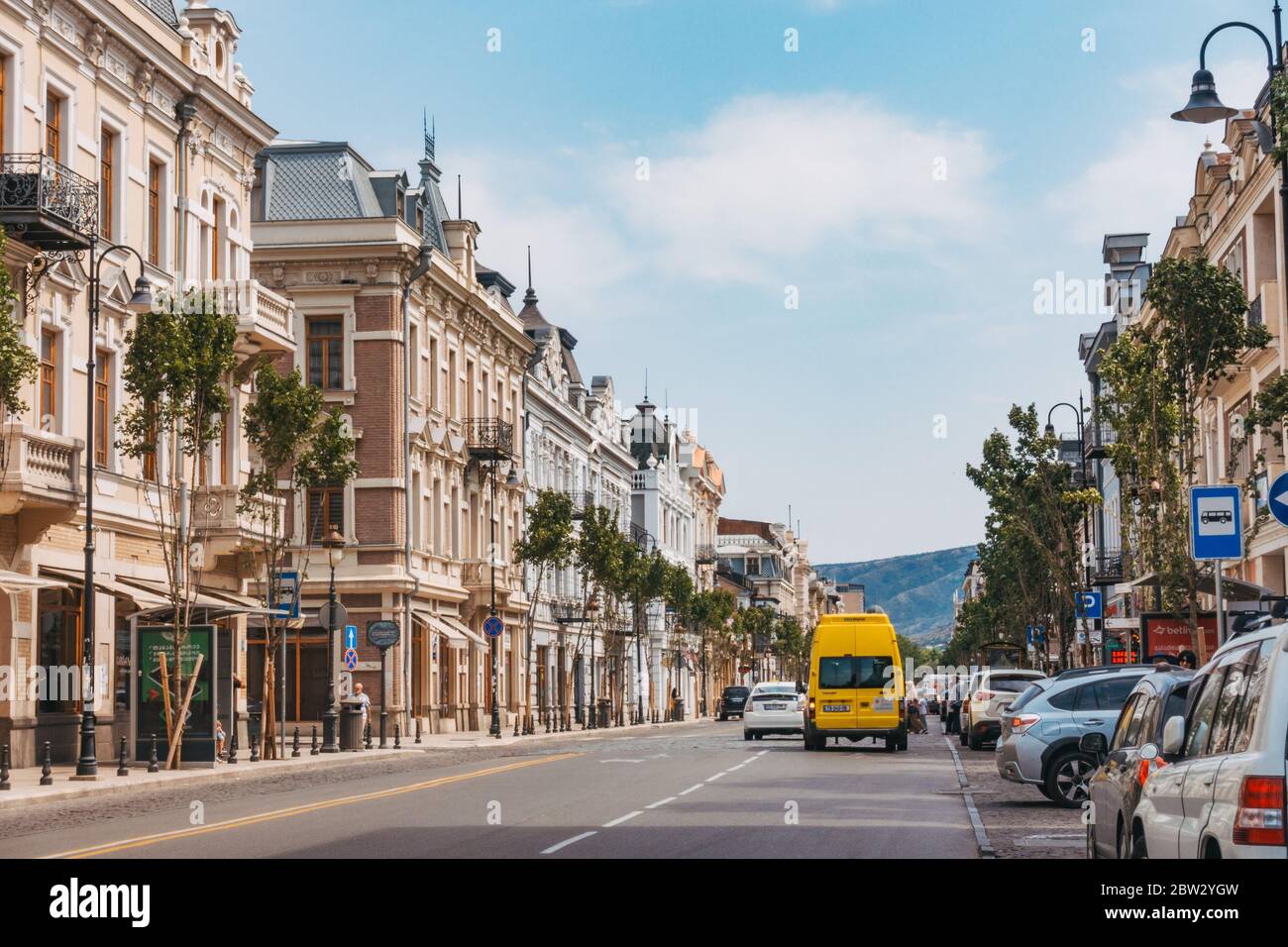 A yellow marshrutka (public minivan) makes its way down the historic ...