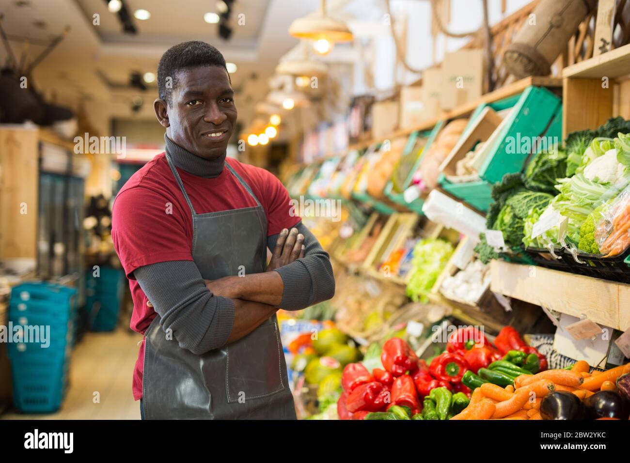 Portrait of friendly confident African American salesman of fruit and ...