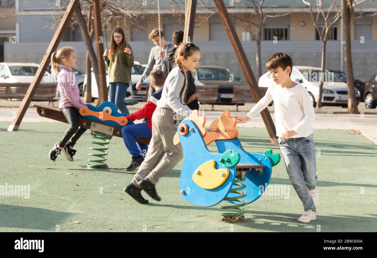 Kids spending time together outdoors playing and talking on see-saw and ...