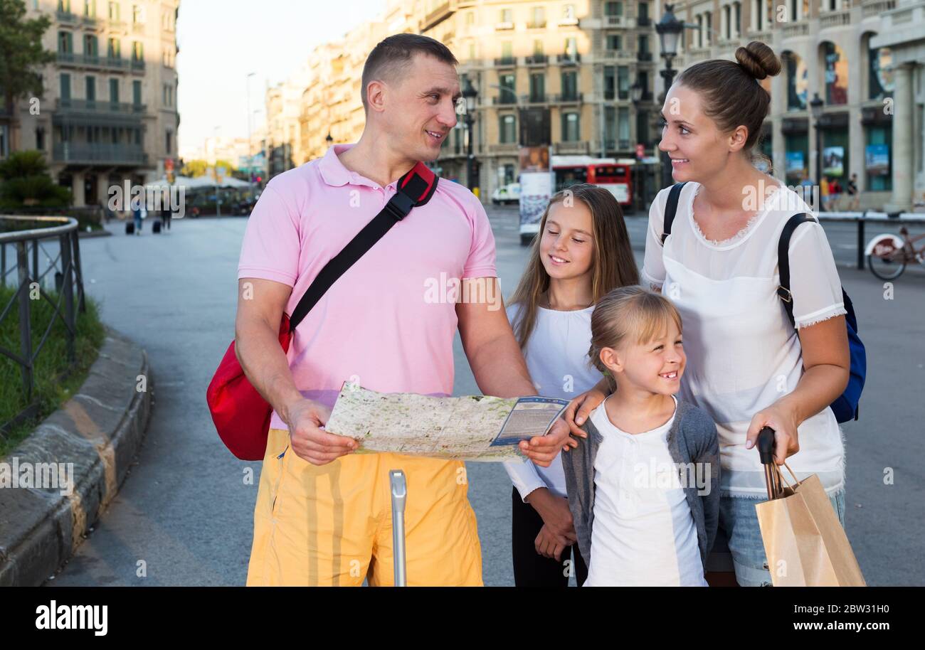 Cheerful family of tourists with two children looking for destination ...