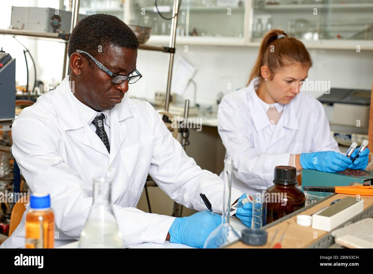 Serious man lab scientist in glasses working with reagents and test ...