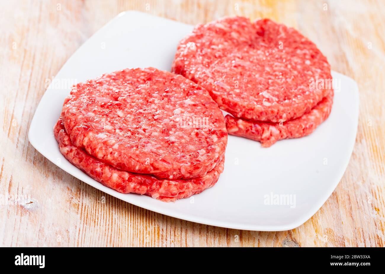 Raw formed minced beef patties for hamburgers ready for frying on plate ...