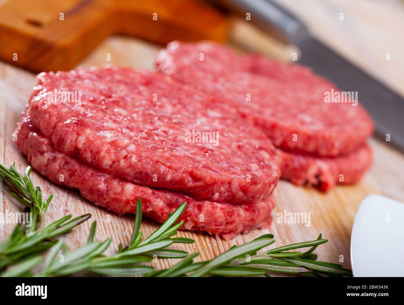 Raw formed hamburger patties ready for frying on wooden table with ...