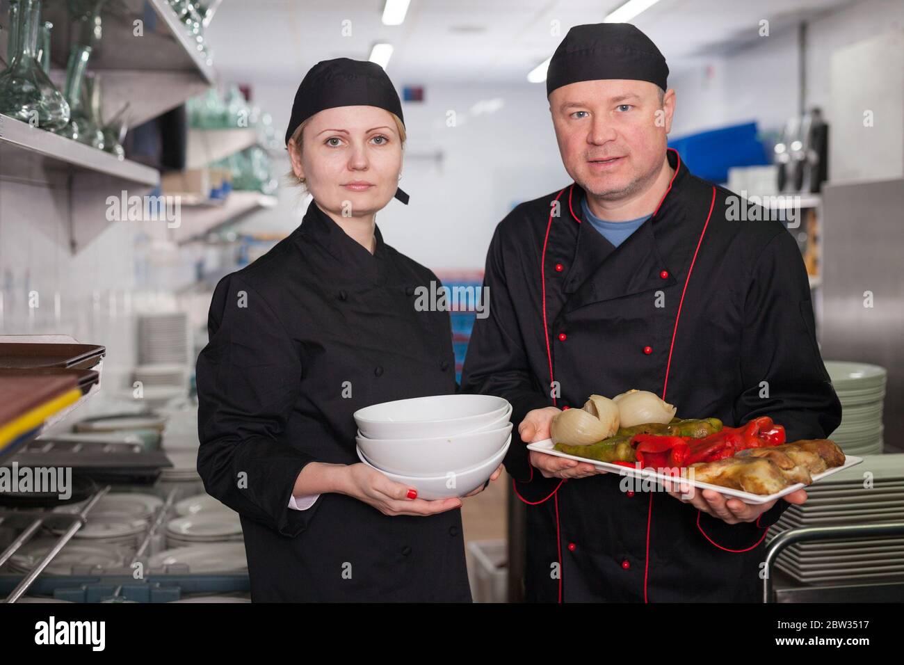 Proud male chef standing with female assistant in restaurant kitchen ...