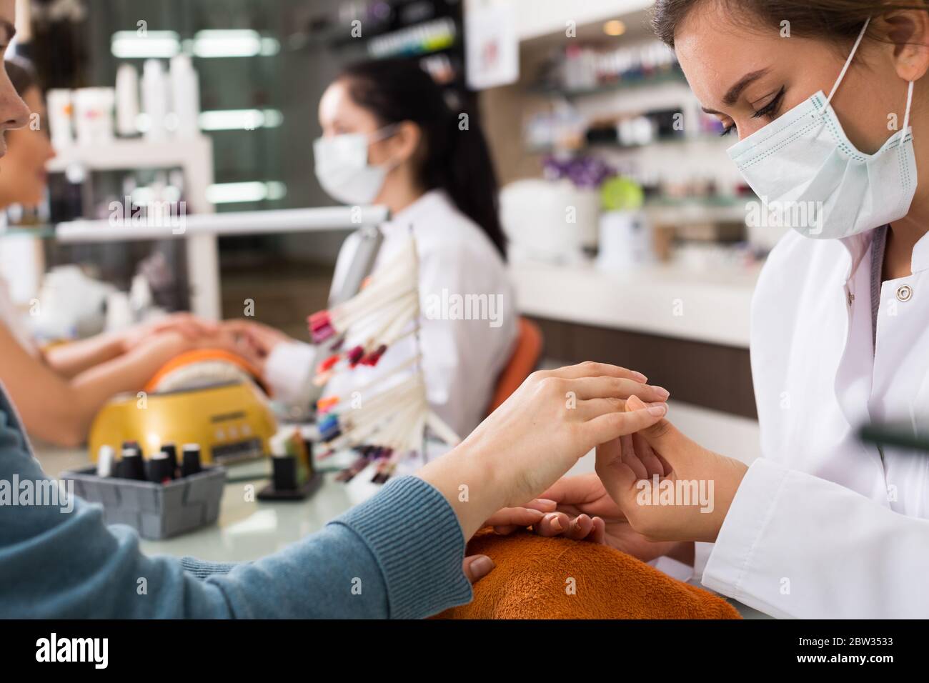 Manicurists giving manicure to female clients at nail salon Stock Photo ...