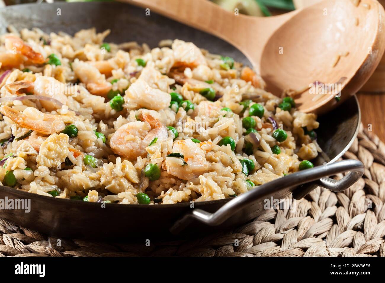 Fried rice with shrimp and vegetables on a frying pan. Popular chinese ...