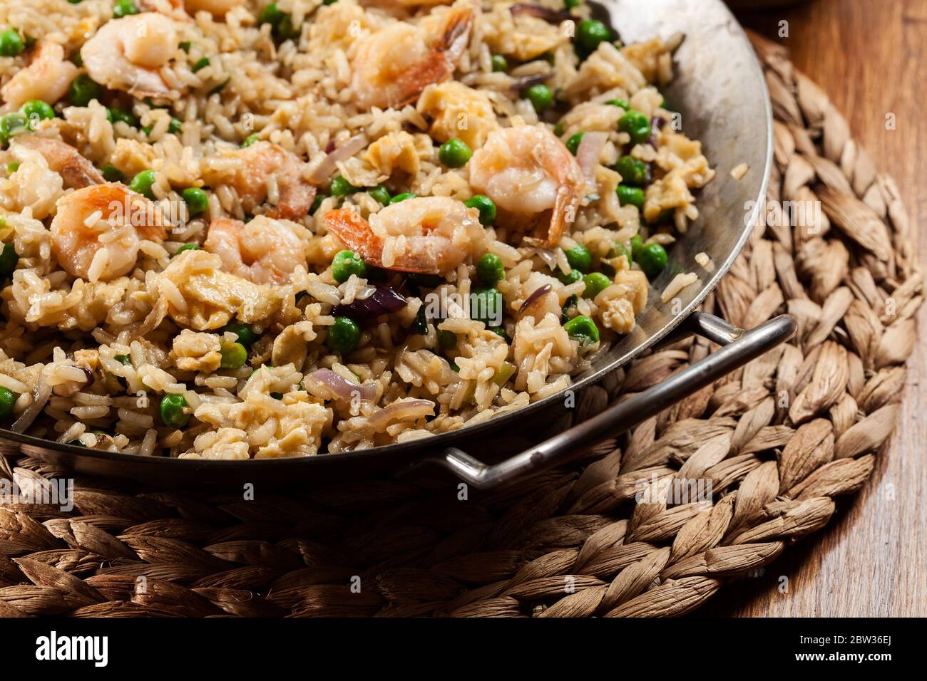 Fried rice with shrimp and vegetables on a frying pan. Popular chinese ...