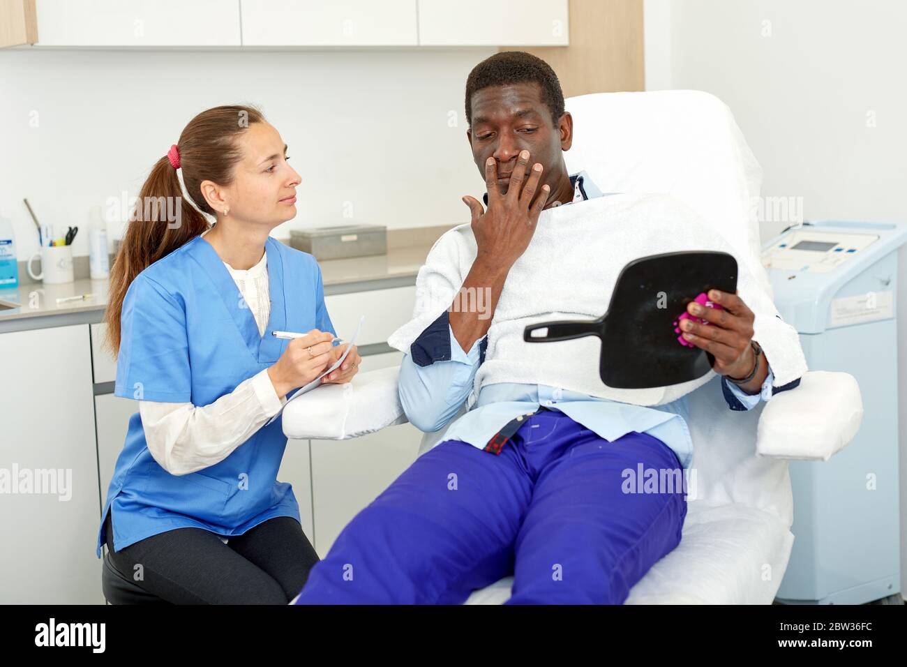 Male client with mirror having conversation with cosmetologist before ...