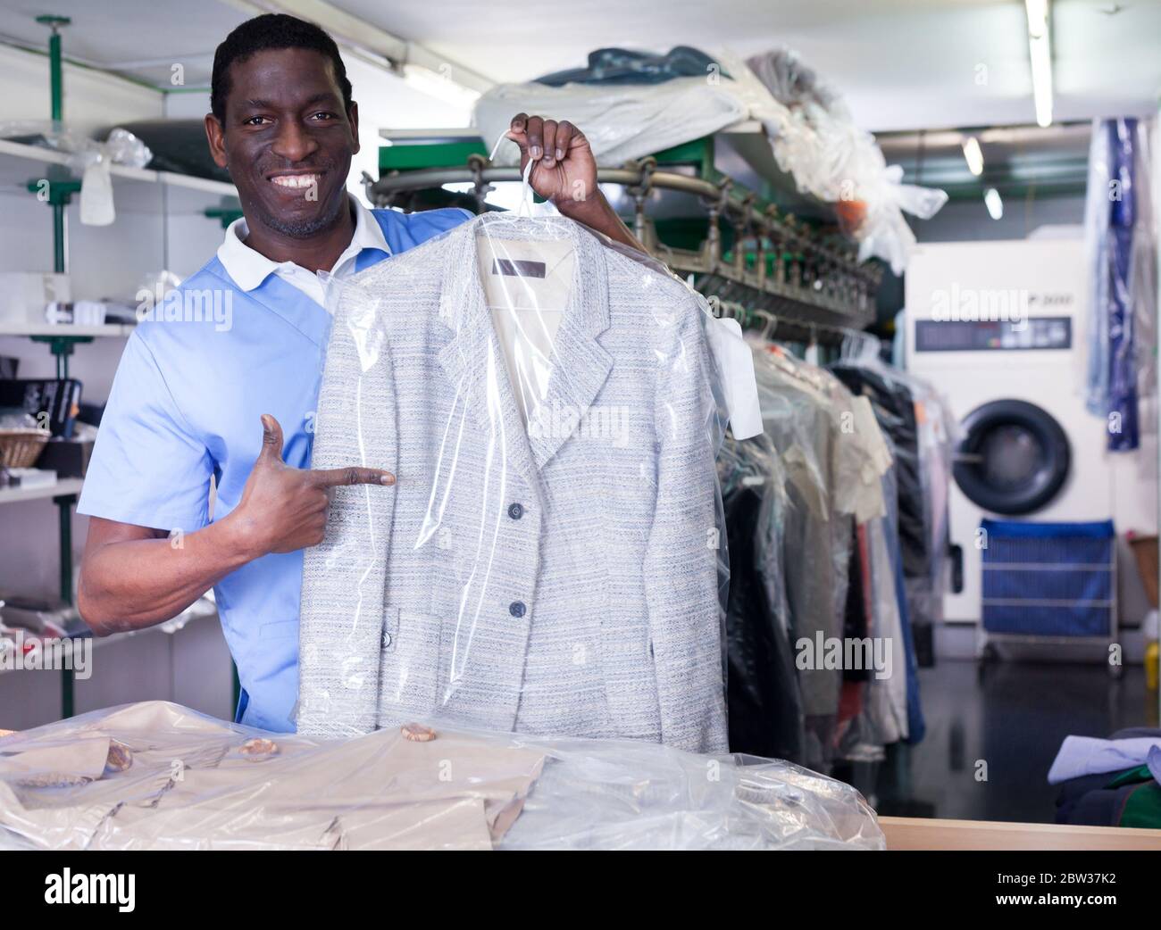 Cheerful African American man worker of dry cleaner standing at ...