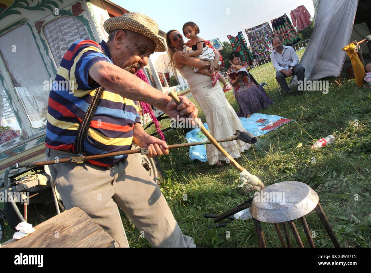 Cracow. Krakow. Poland. Old Gypsy craftsman, tinsmith tiining the iron ...