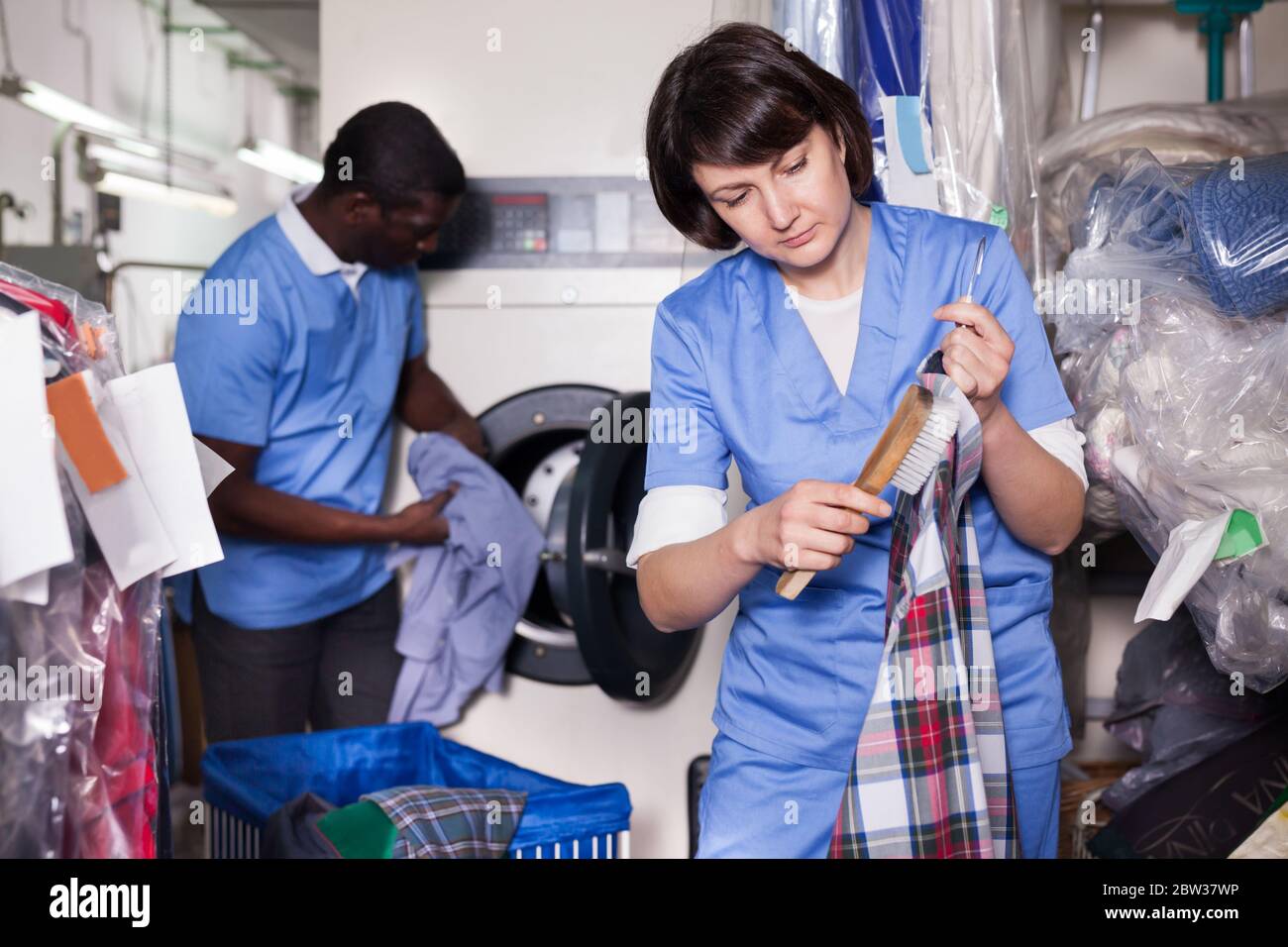 Focused young woman dry cleaning clothes in laundry Stock Photo - Alamy