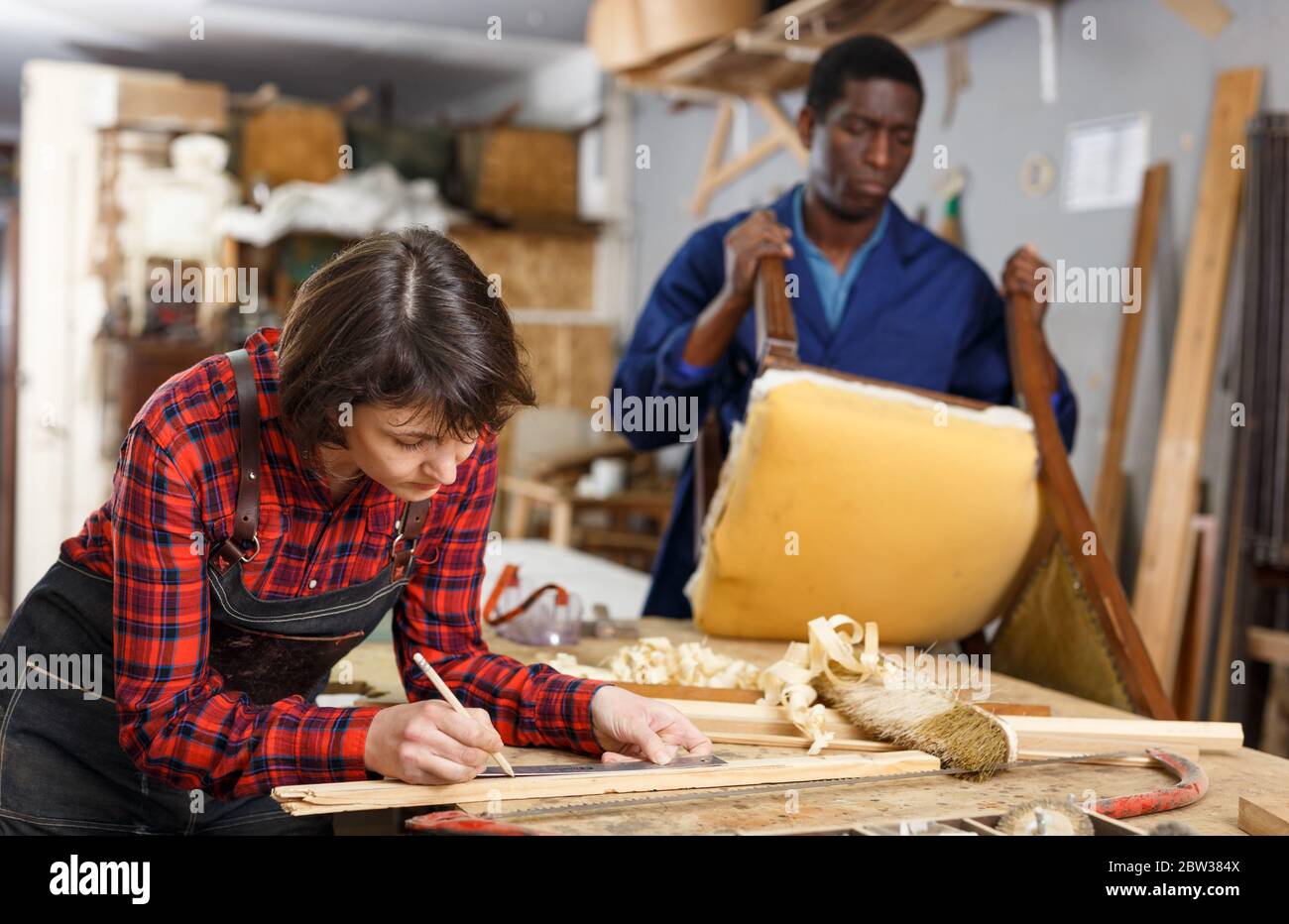 Woman and man carpenters using tools for restoration wooden chair in ...