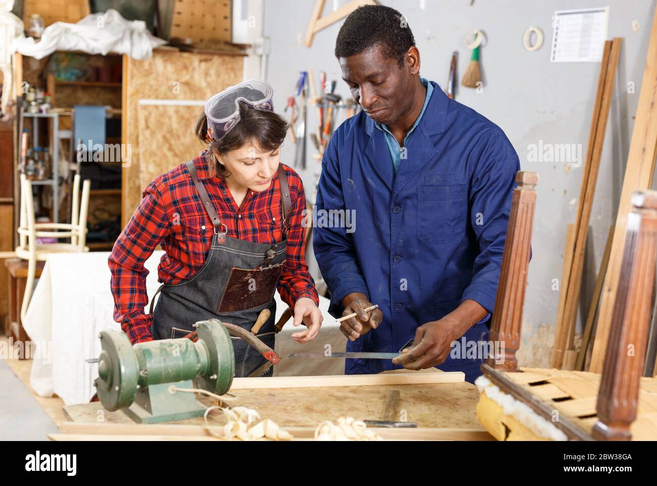 Woman and man carpenters using tools for restoration wooden chair in ...