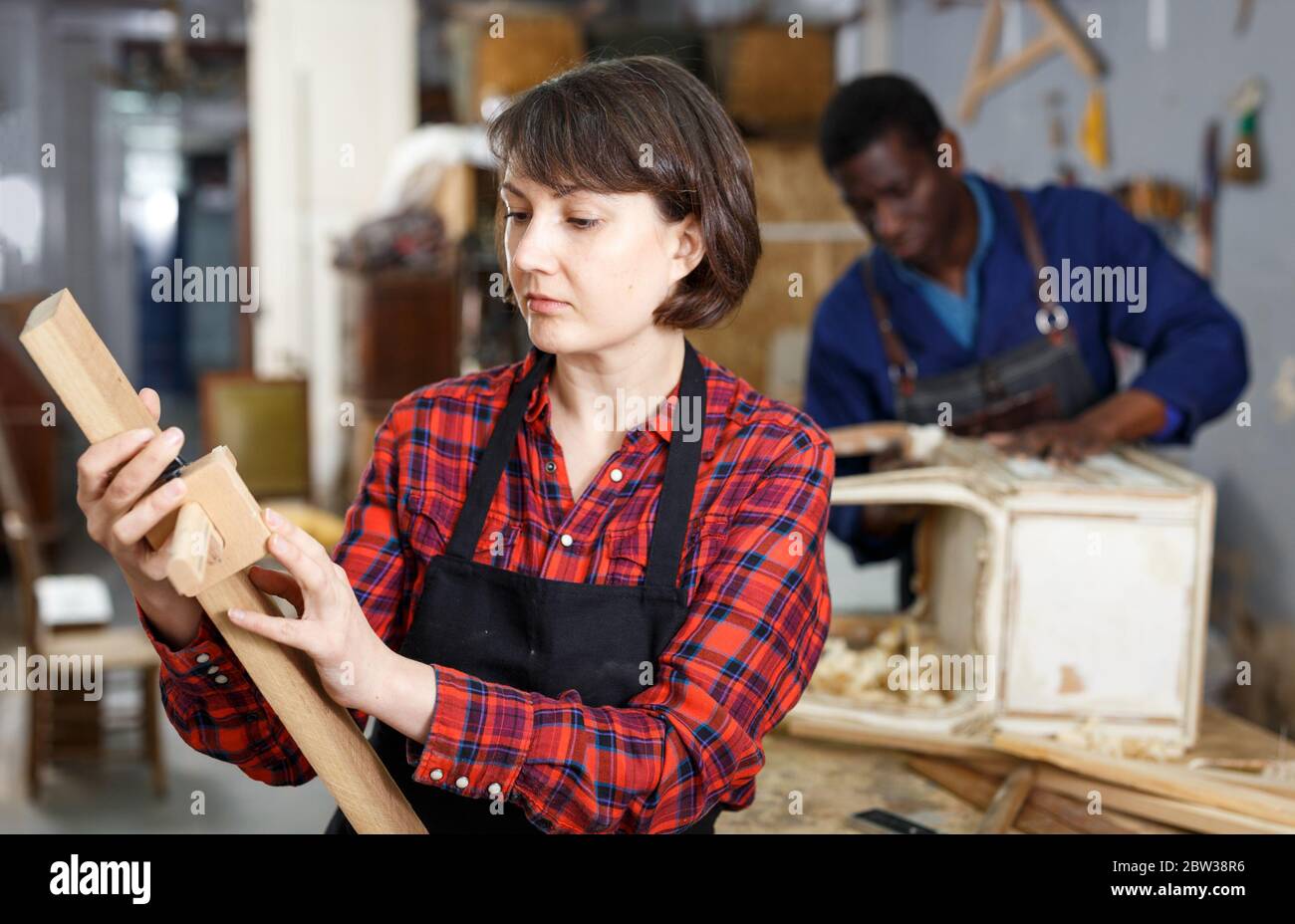 Woman carpenter using tools for creating wooden furniture in studio ...