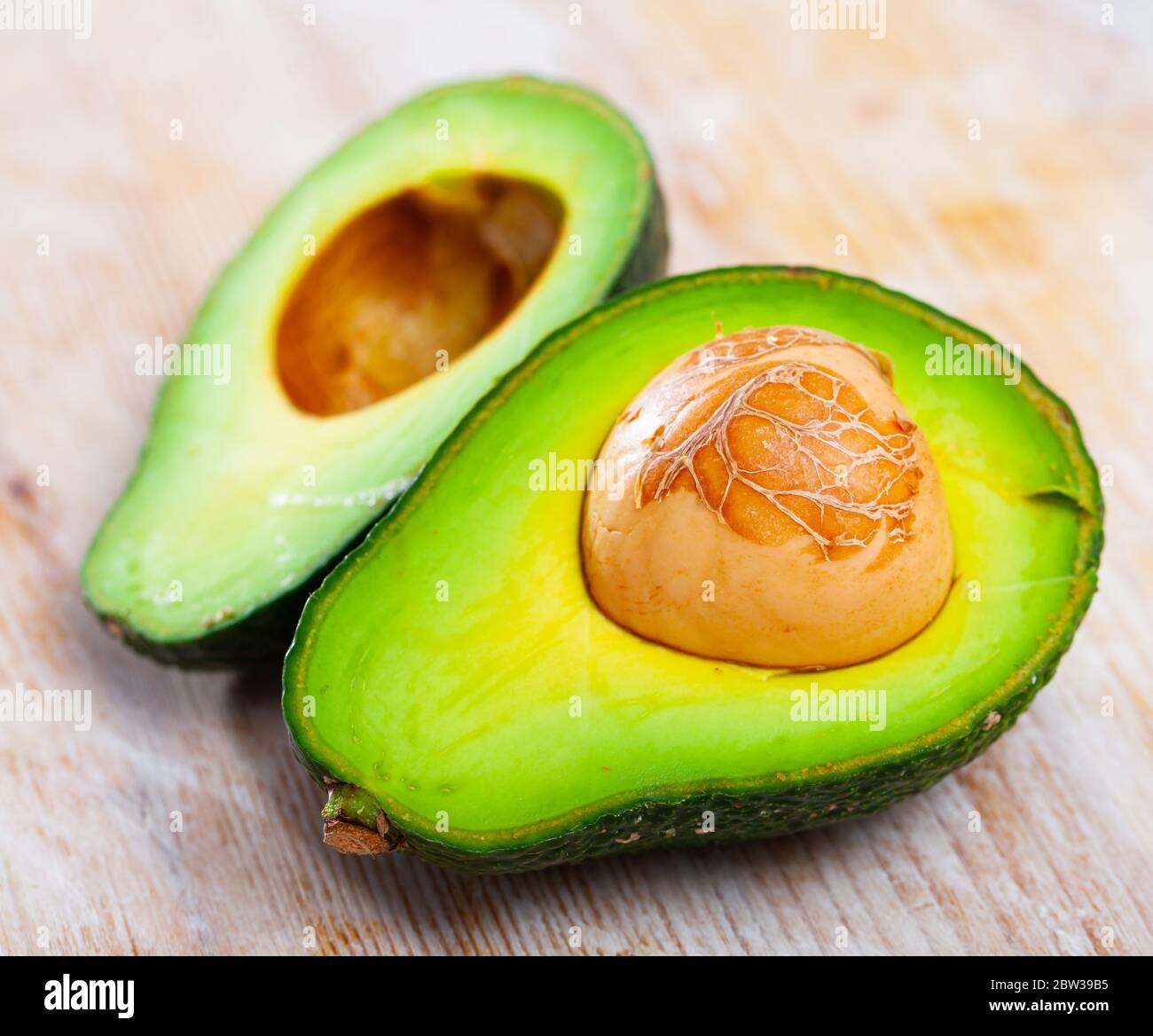 Image of close up of cut avocado with bone at wooden table Stock Photo ...