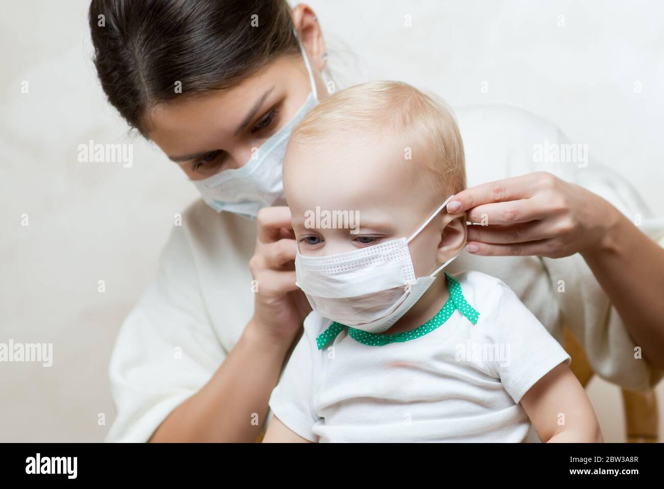 mom puts on a medical face mask to her little daughter Stock Photo - Alamy