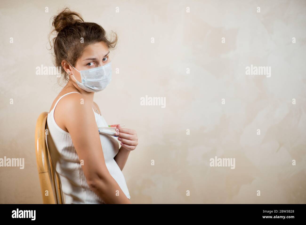 a sickly-looking girl in a protective medical mask looks sadly at the ...
