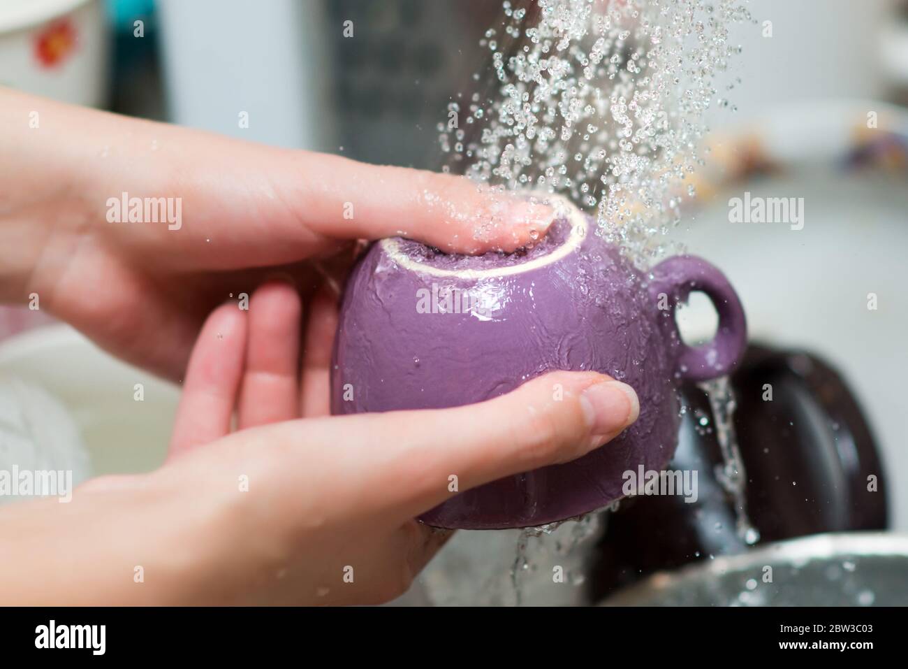 Girl rinses a cup under running water, close up Stock Photo - Alamy