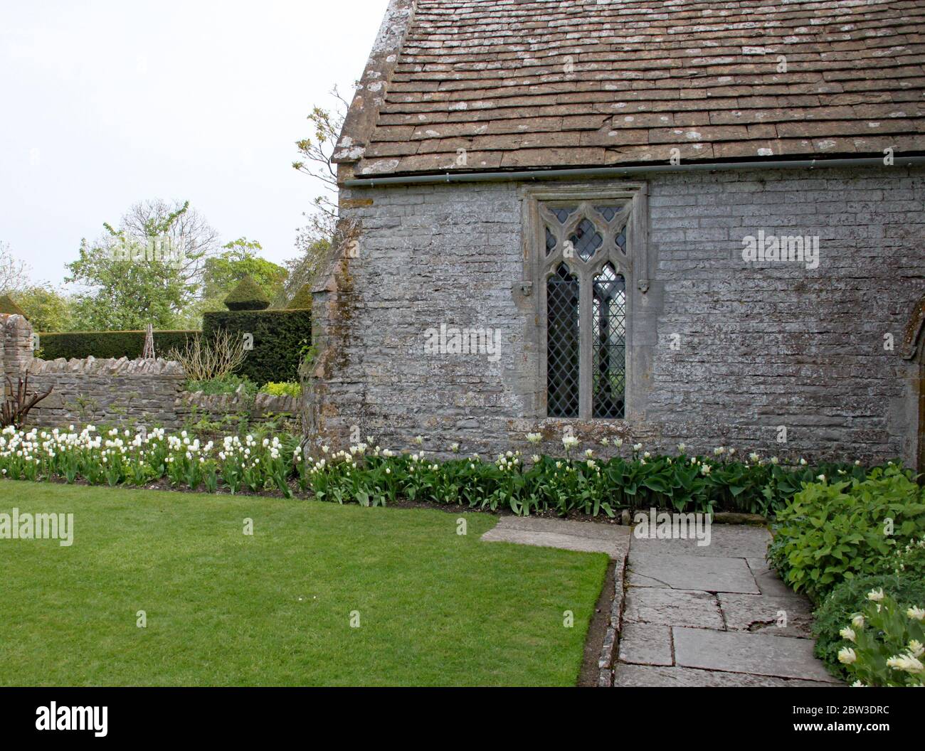A pathway runs along the side of a verdant lawn to the entrance of a ...