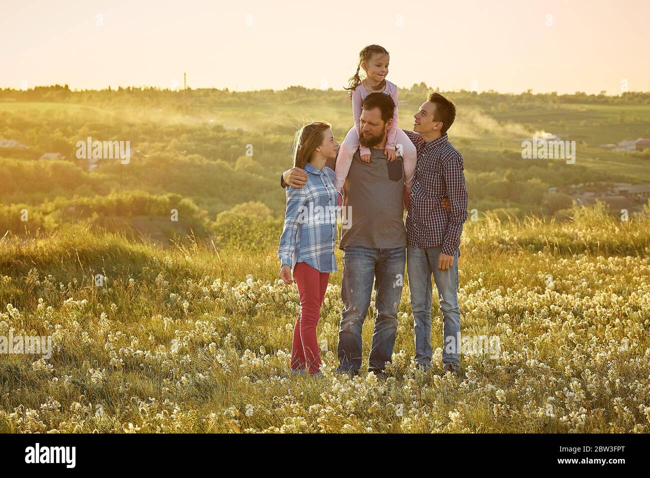 a father with three children in nature, a man hugs his daughters and ...