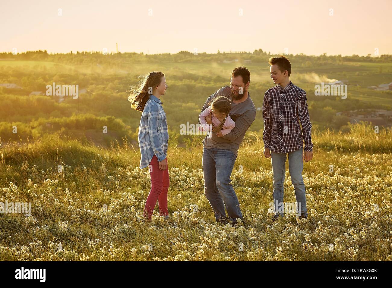 a father with three children in nature, a man hugs his daughters and ...