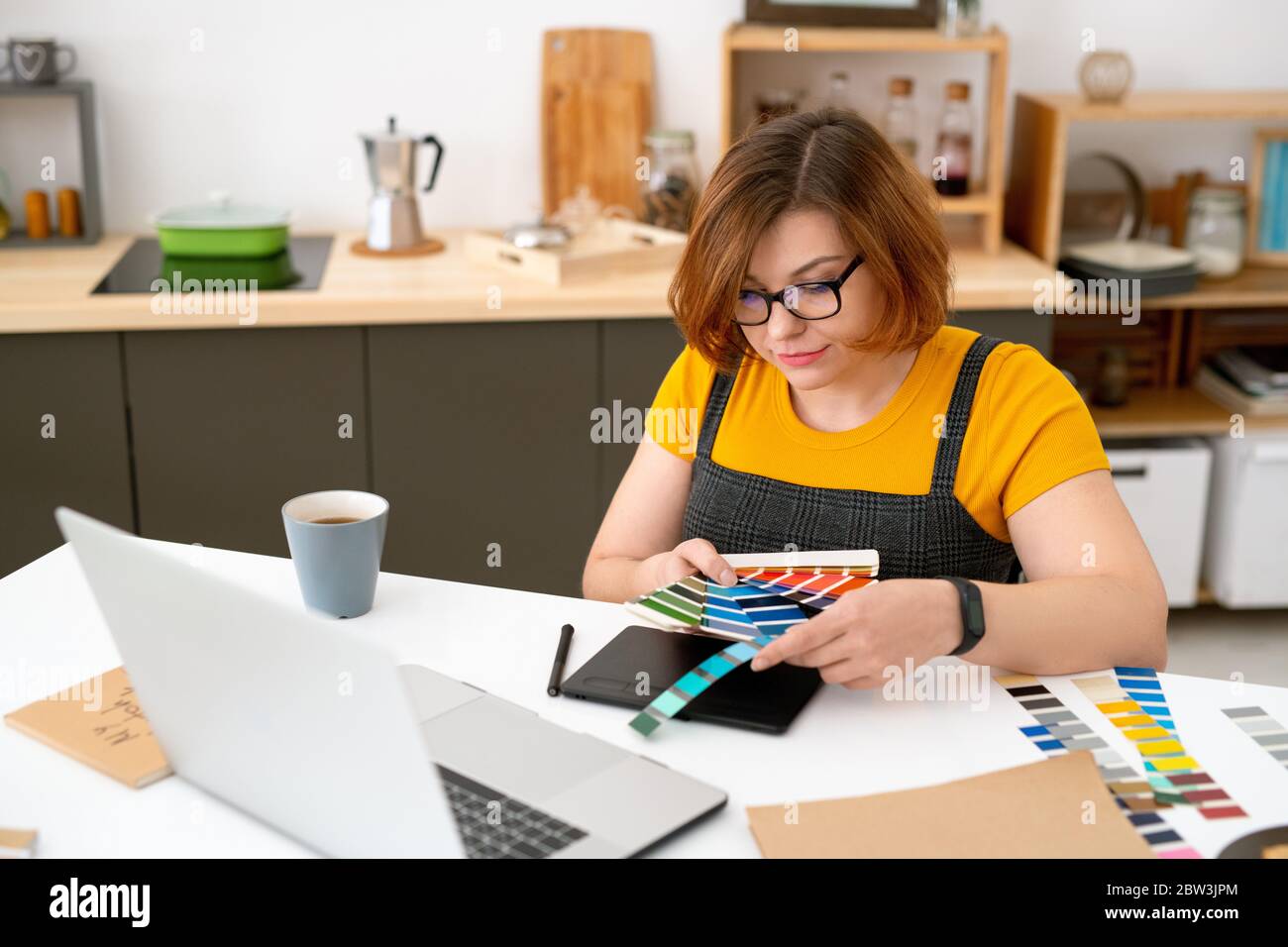 Creative young web designer sitting at desk and looking at color ...
