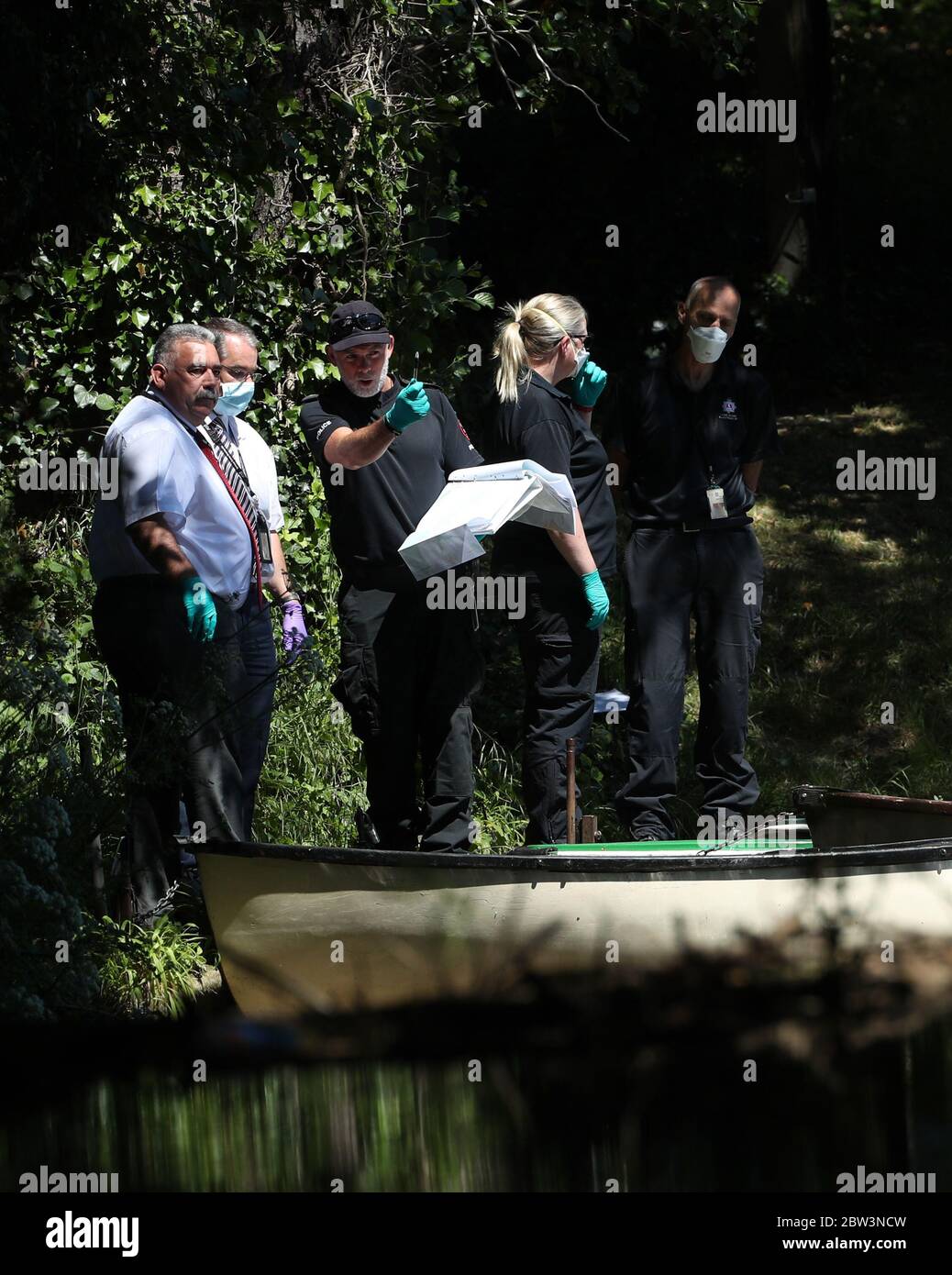 Police forensic officers looking round the boats by the lake on the ...