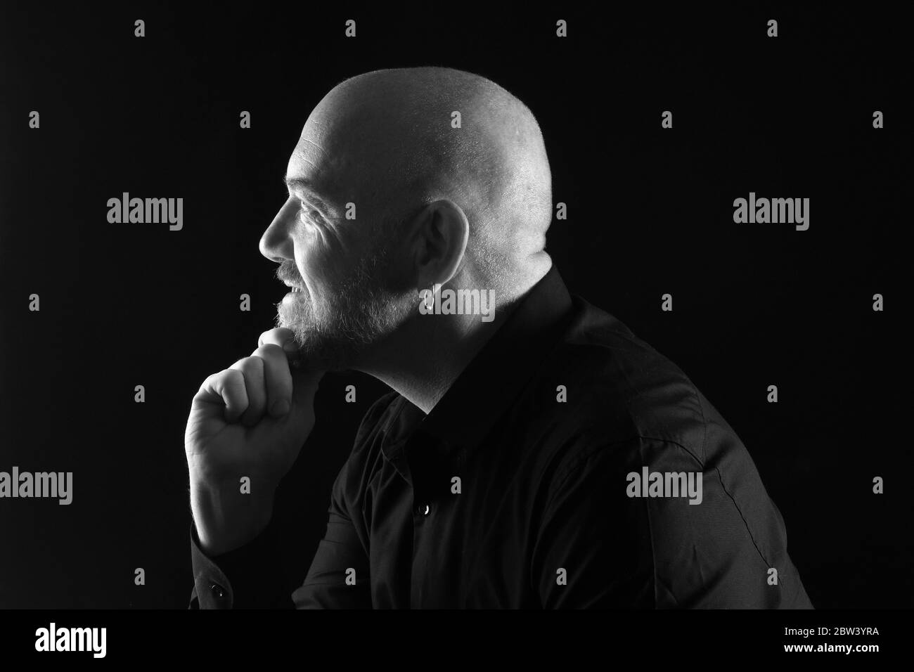 portrait of a man in low key, smiling and looking side black and withe ...