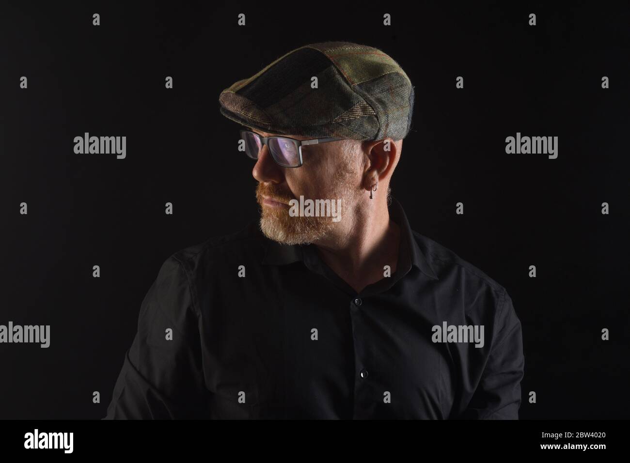 portrait of a man in low key,looking side clothing with cap and eyewear ...
