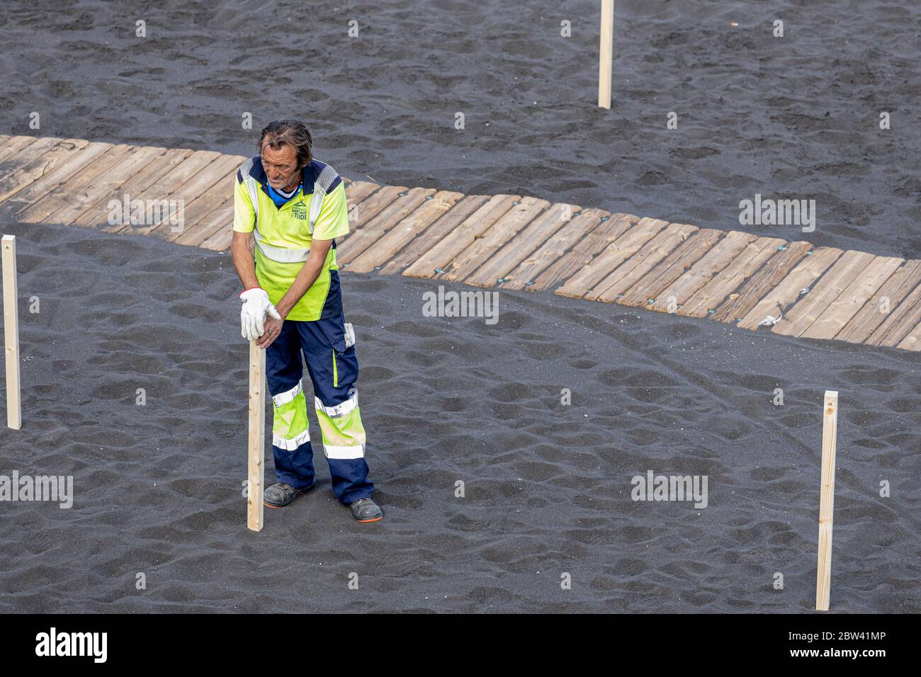 Workers prepare the beach with cordoned off areas to maintain social ...