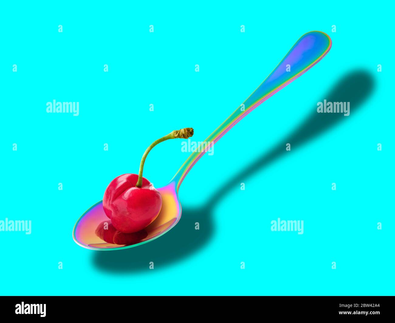 Red cherry on colorful spoon Stock Photo - Alamy