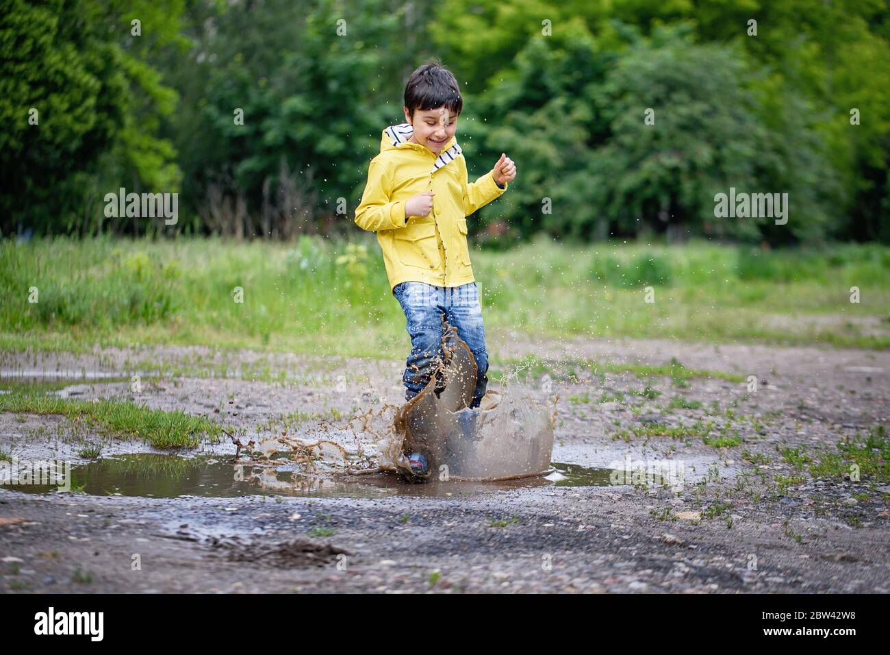 wet child jumping in puddle. Fun on street. Tempering in summer ...