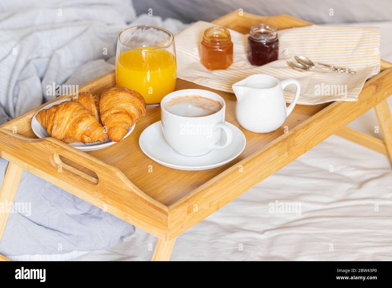 Breakfast on the bed inside a bedroom. Cup of coffee, orange juice ...