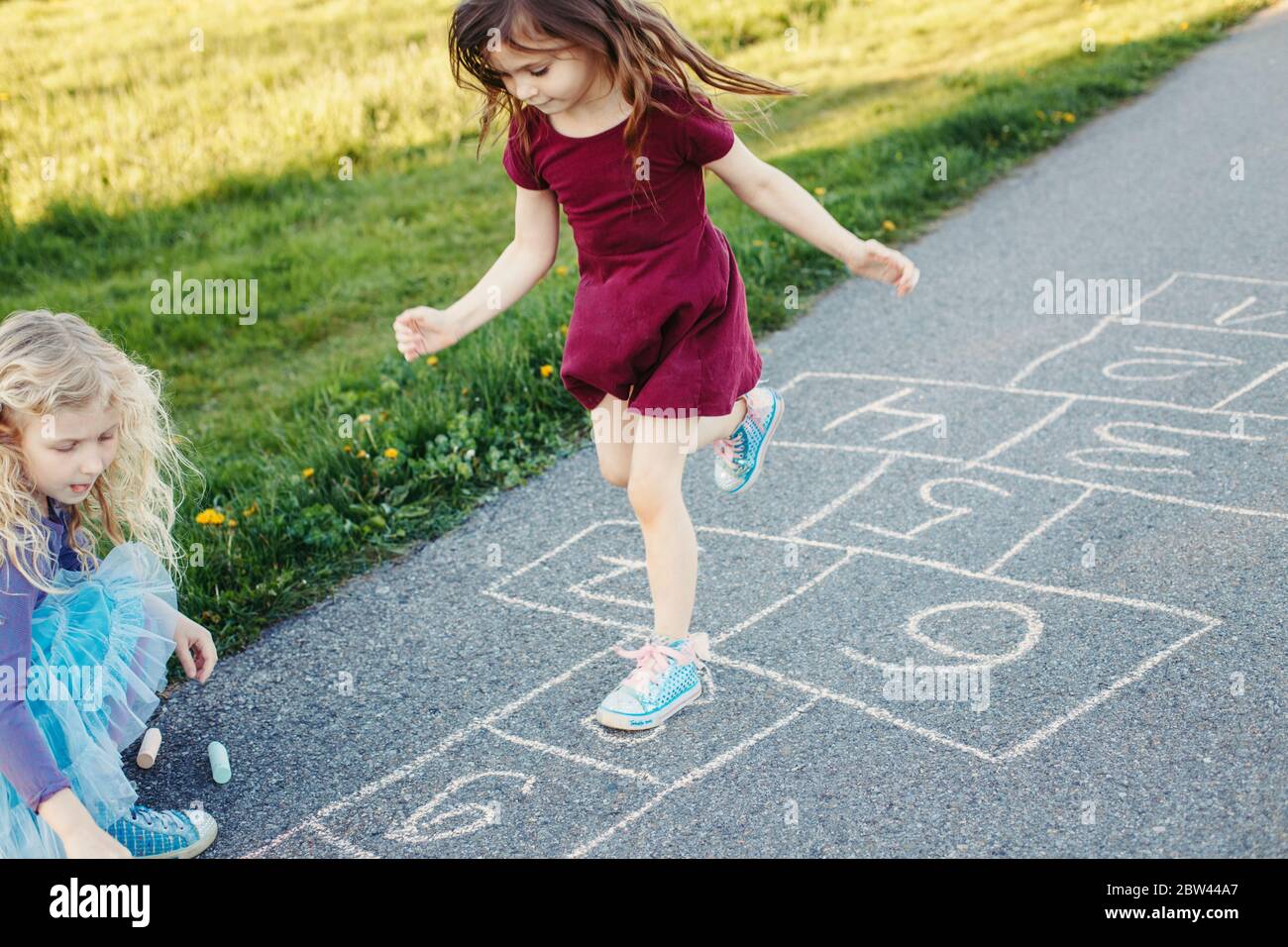 Cute adorable children girls friends playing jumping hopscotch outdoor ...