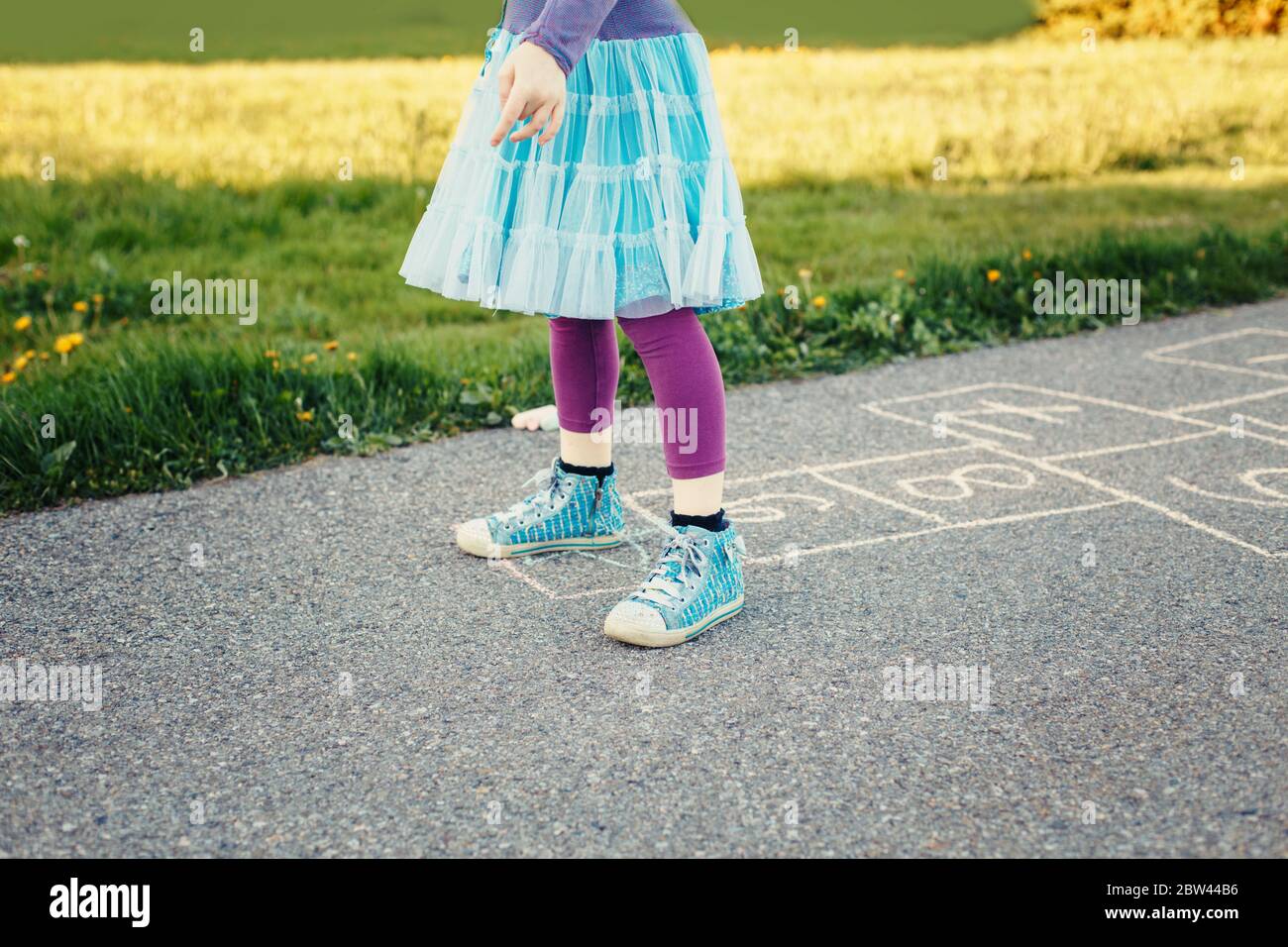 Closeup of child girl playing jumping hopscotch outdoor. Funny activity ...