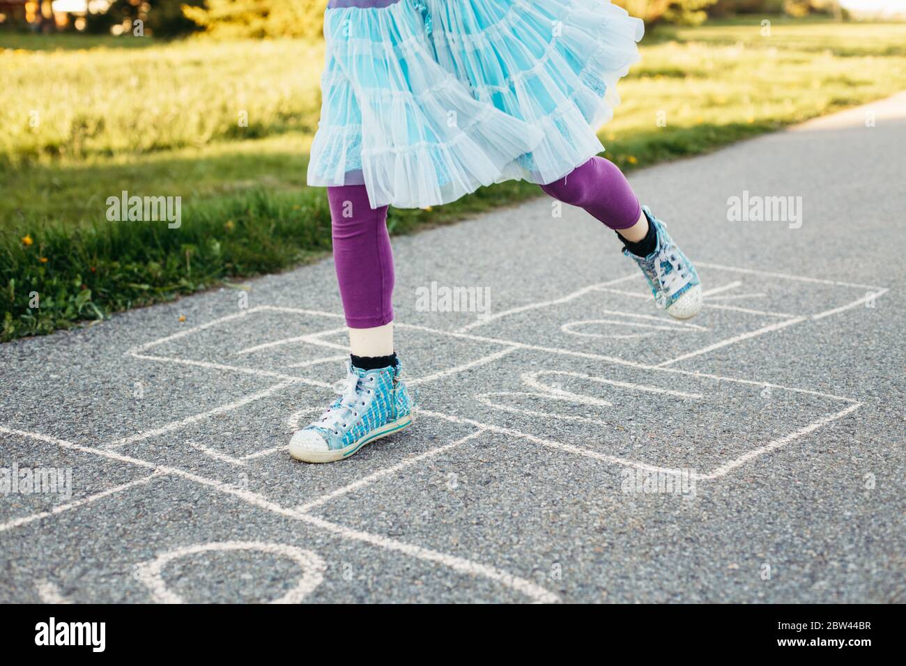 Closeup of child girl playing jumping hopscotch outdoor. Funny activity ...