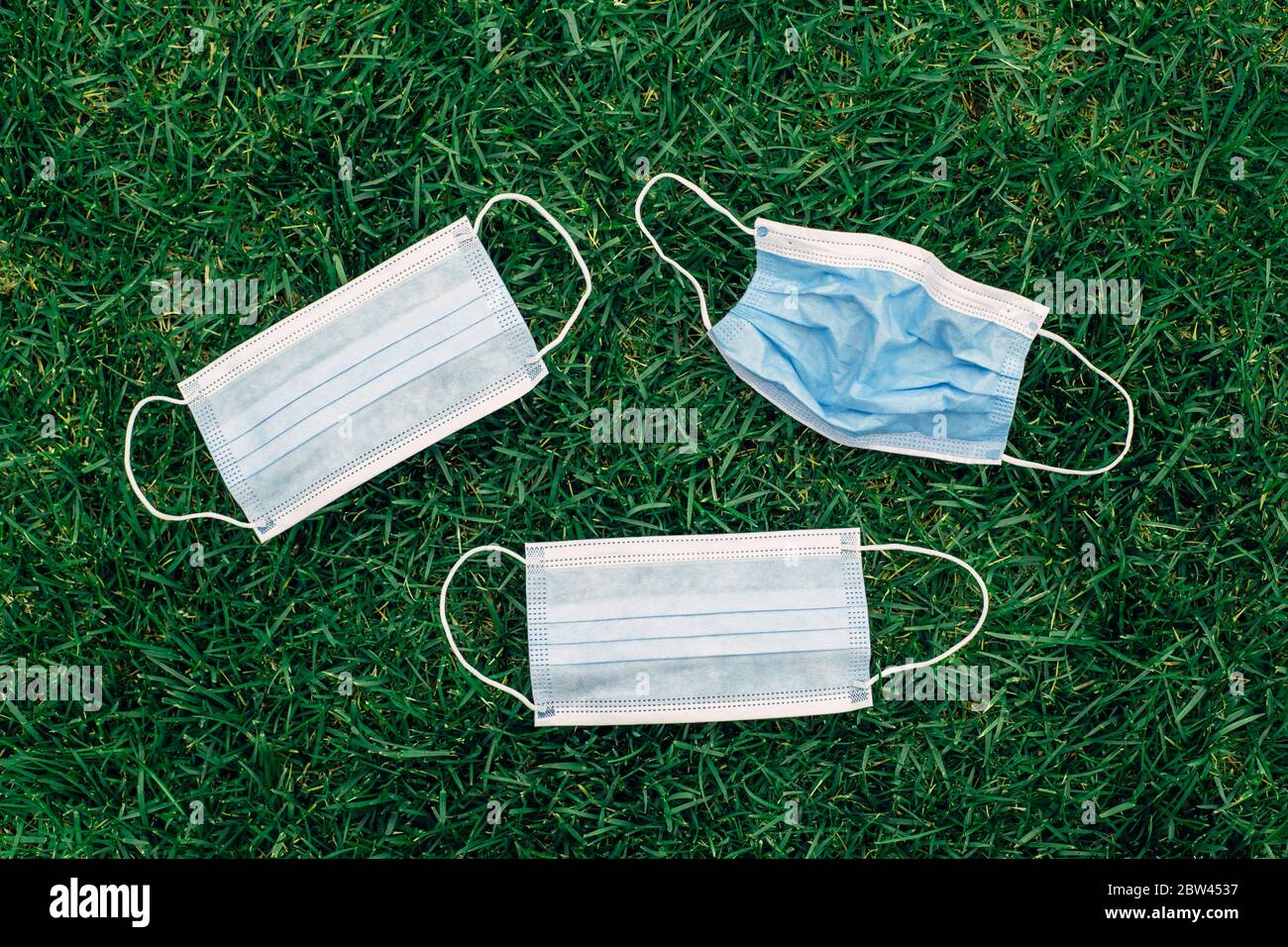 Group of used and fresh sanitary masks lying on grass. Disposable ...