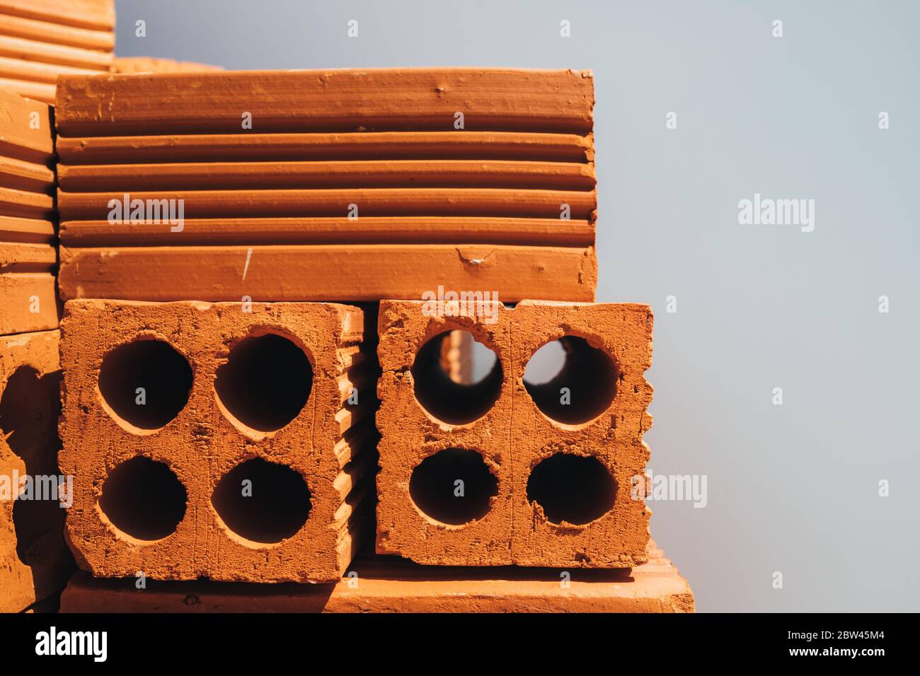 Hollow red bricks piled in a pile, ready for use in construction or for ...