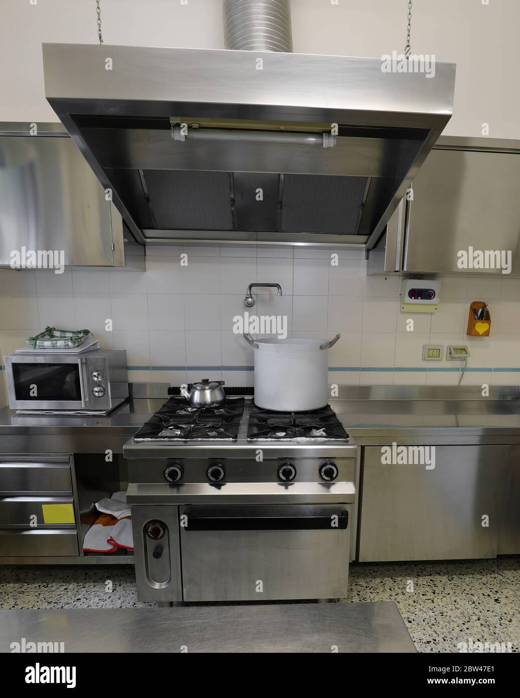 large aluminum pot in the industrial kitchen and the tap above the ...