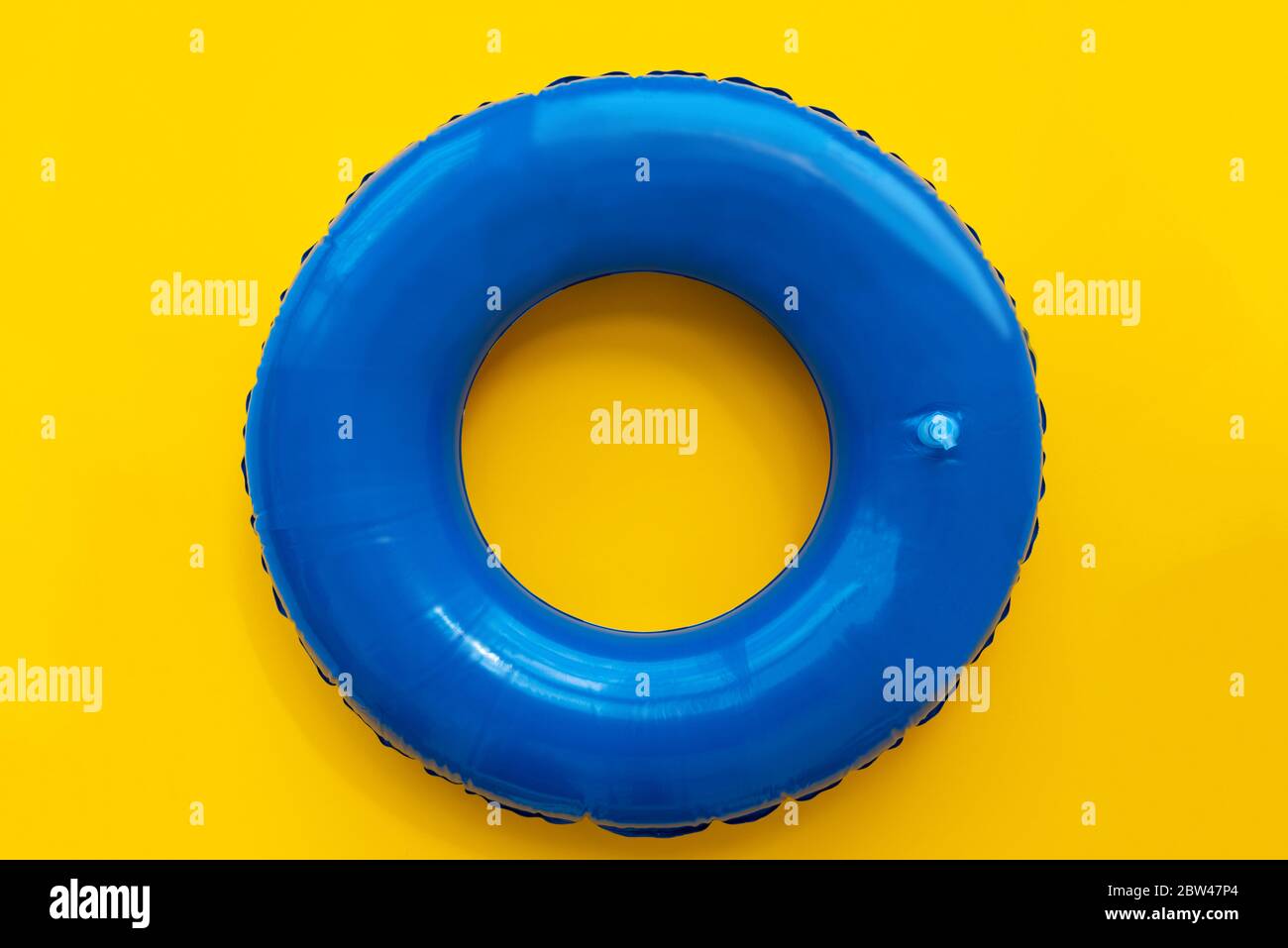 Front view of blue rubber ring for swimming pool on yellow background ...