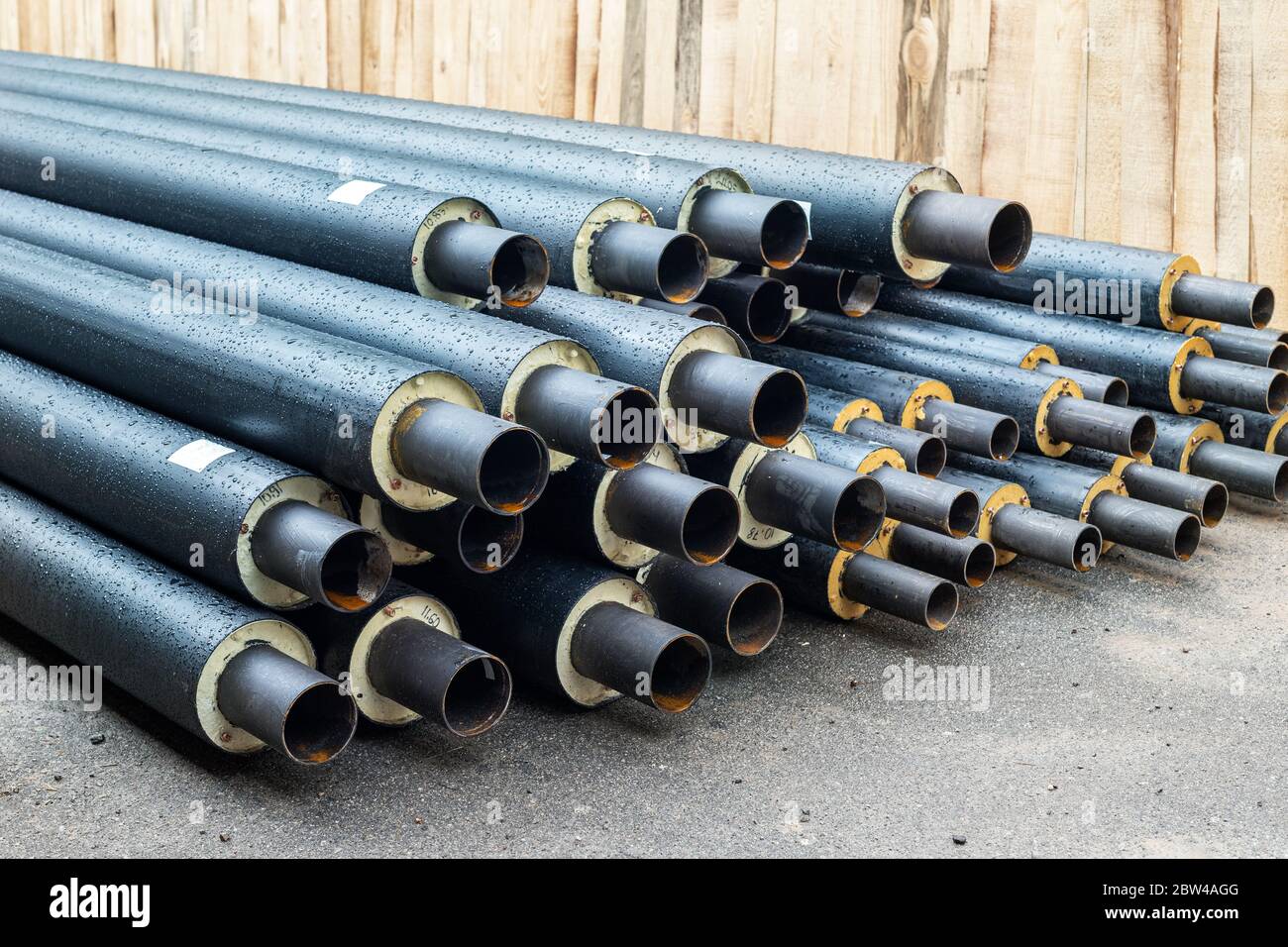 Heap of many new black insulated steel pipes at municipal construction ...