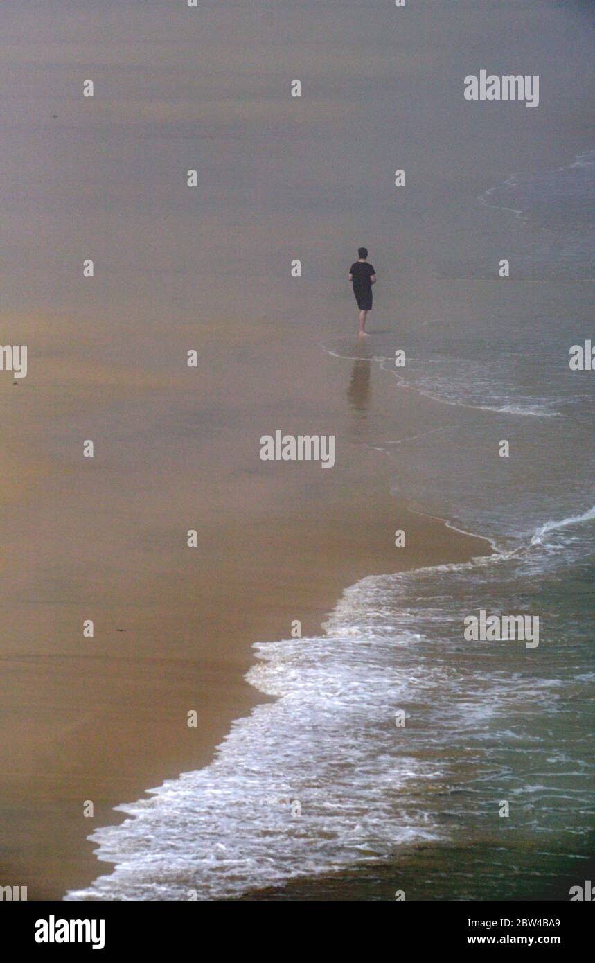 Shoreline, waves, beach and solitary male Stock Photo - Alamy