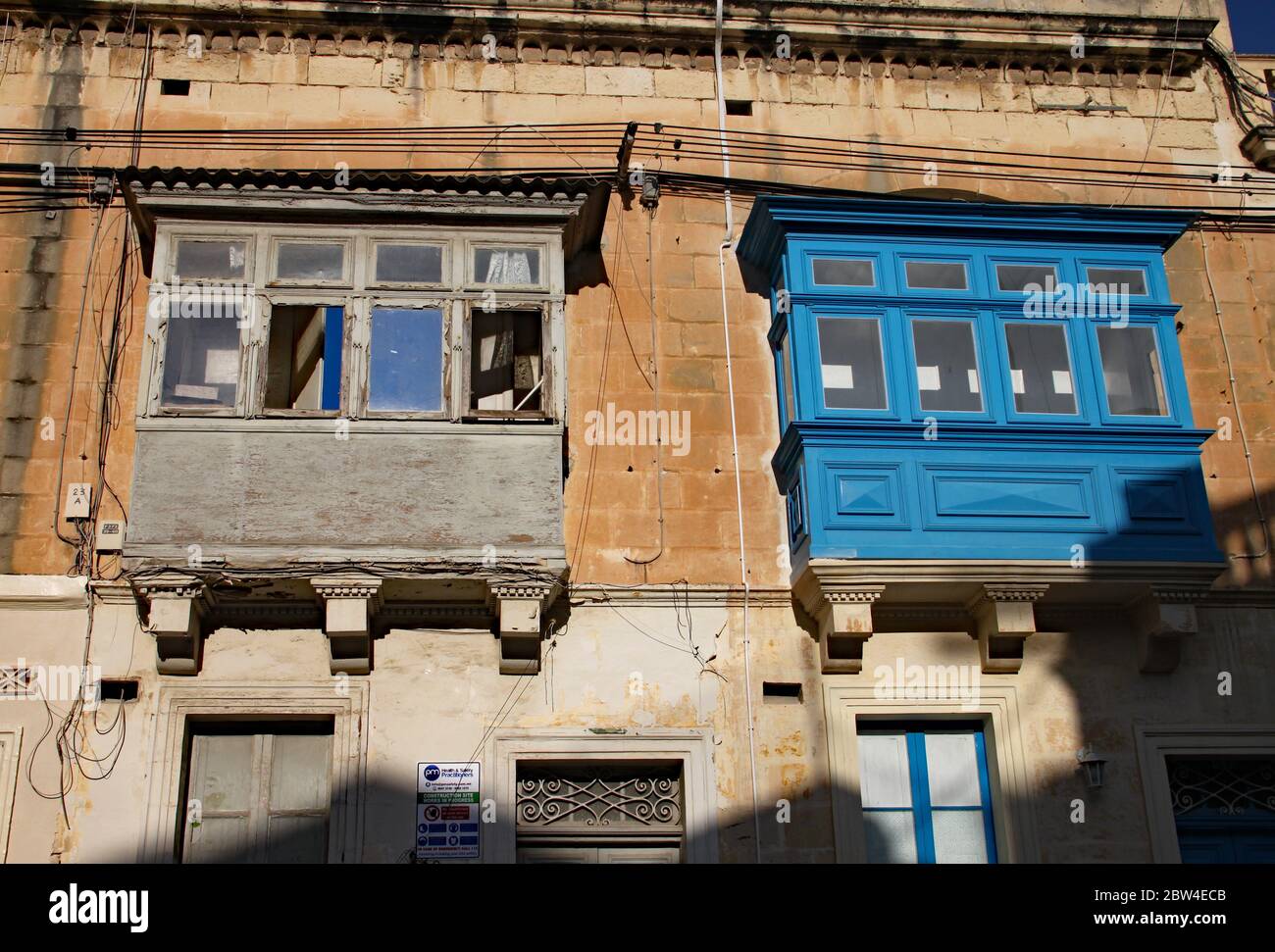 Two bay windows in Sliema in Malta. One window is clean and painted ...
