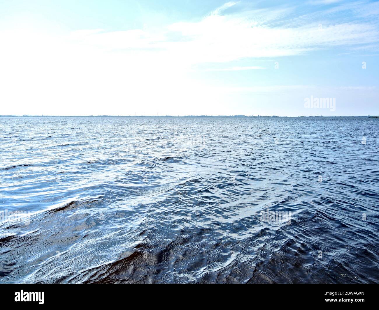 A perfect day at a lake - calm blue water, waves and ripples, pale off ...