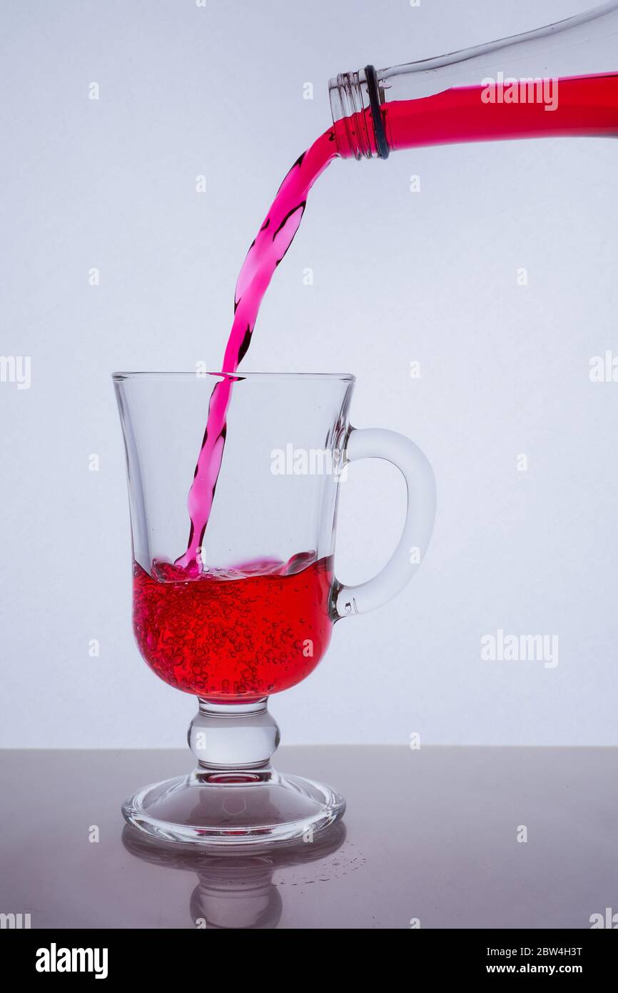 red liquid poured into a glass glass on a white background with bubbles ...