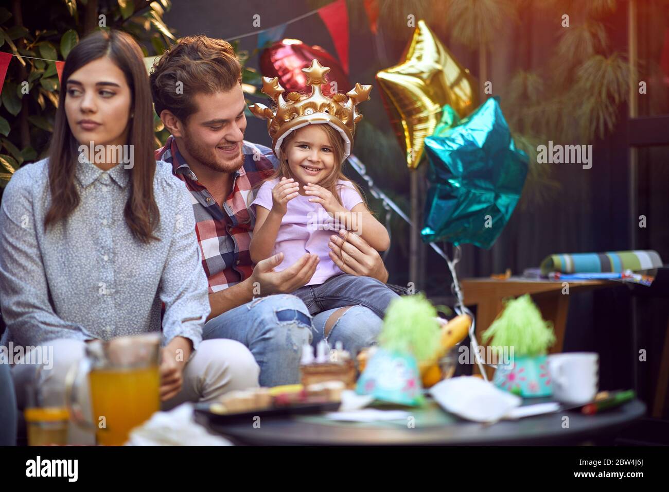 Happy girl with crown at head enjoying at birthday party with family ...