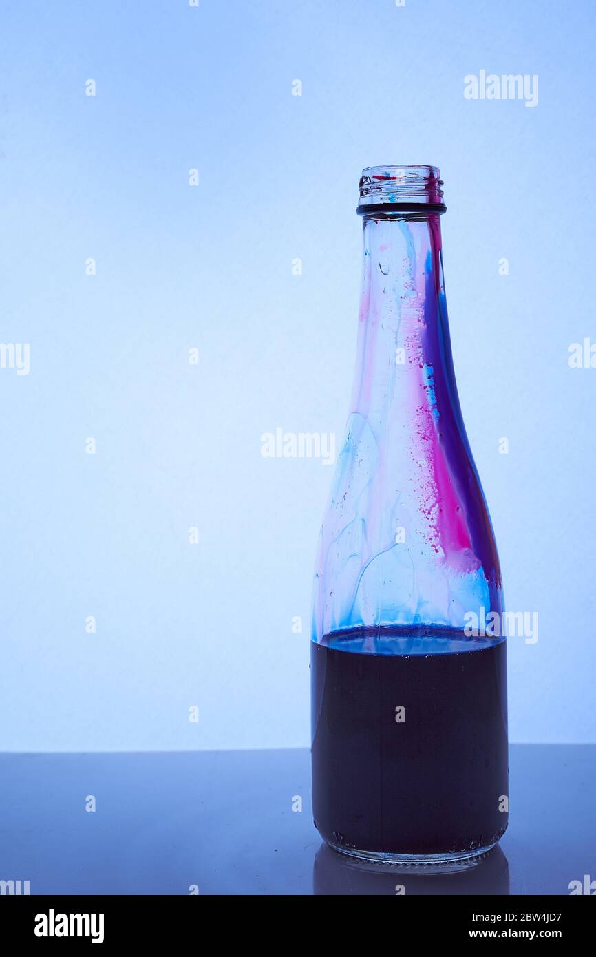 a blue liquid is poured into a glass bottle. Light blue background ...